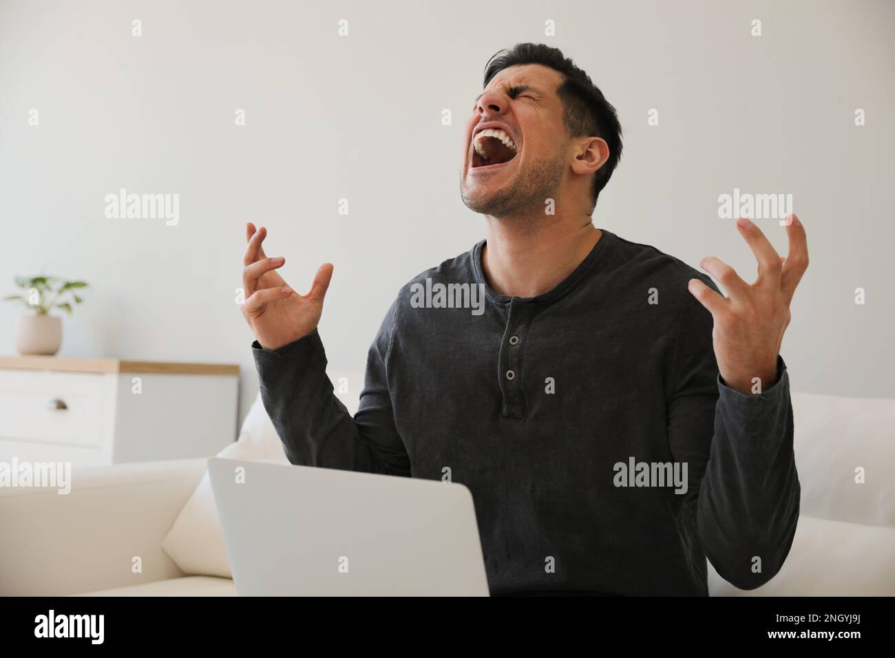 Emotional man working with laptop at home Stock Photo - Alamy
