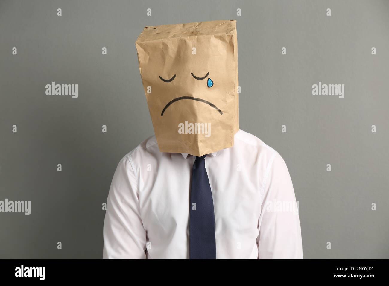Man wearing paper bag with drawn sad face on grey background Stock ...
