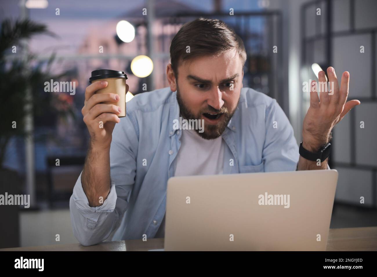 Emotional young man working on laptop in office. Online hate concept ...