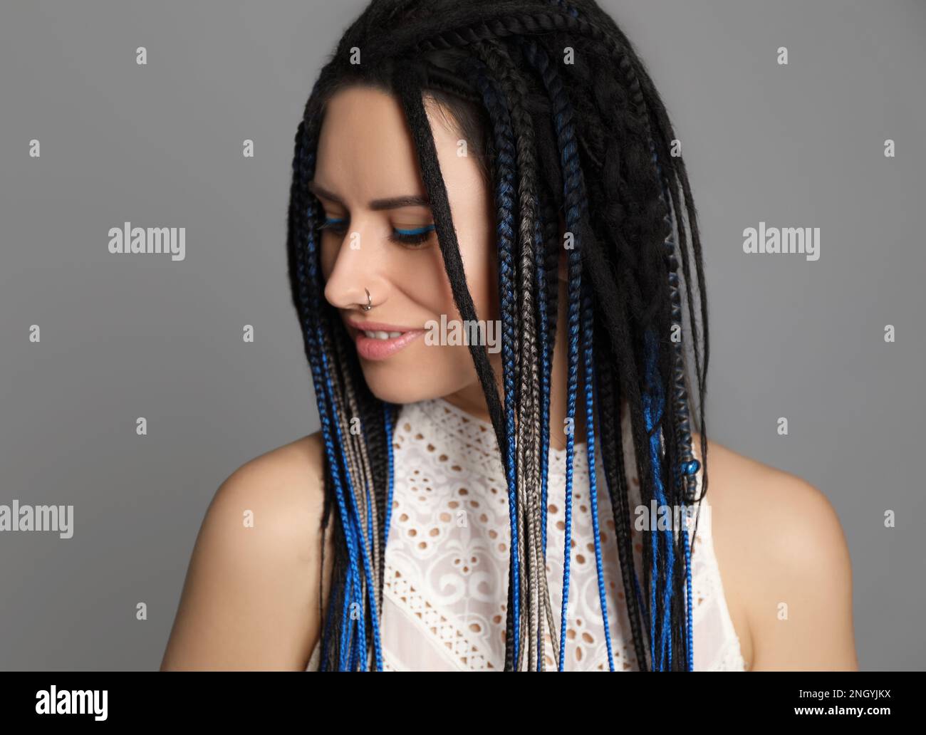 Beautiful young woman with nose piercing and dreadlocks on grey ...