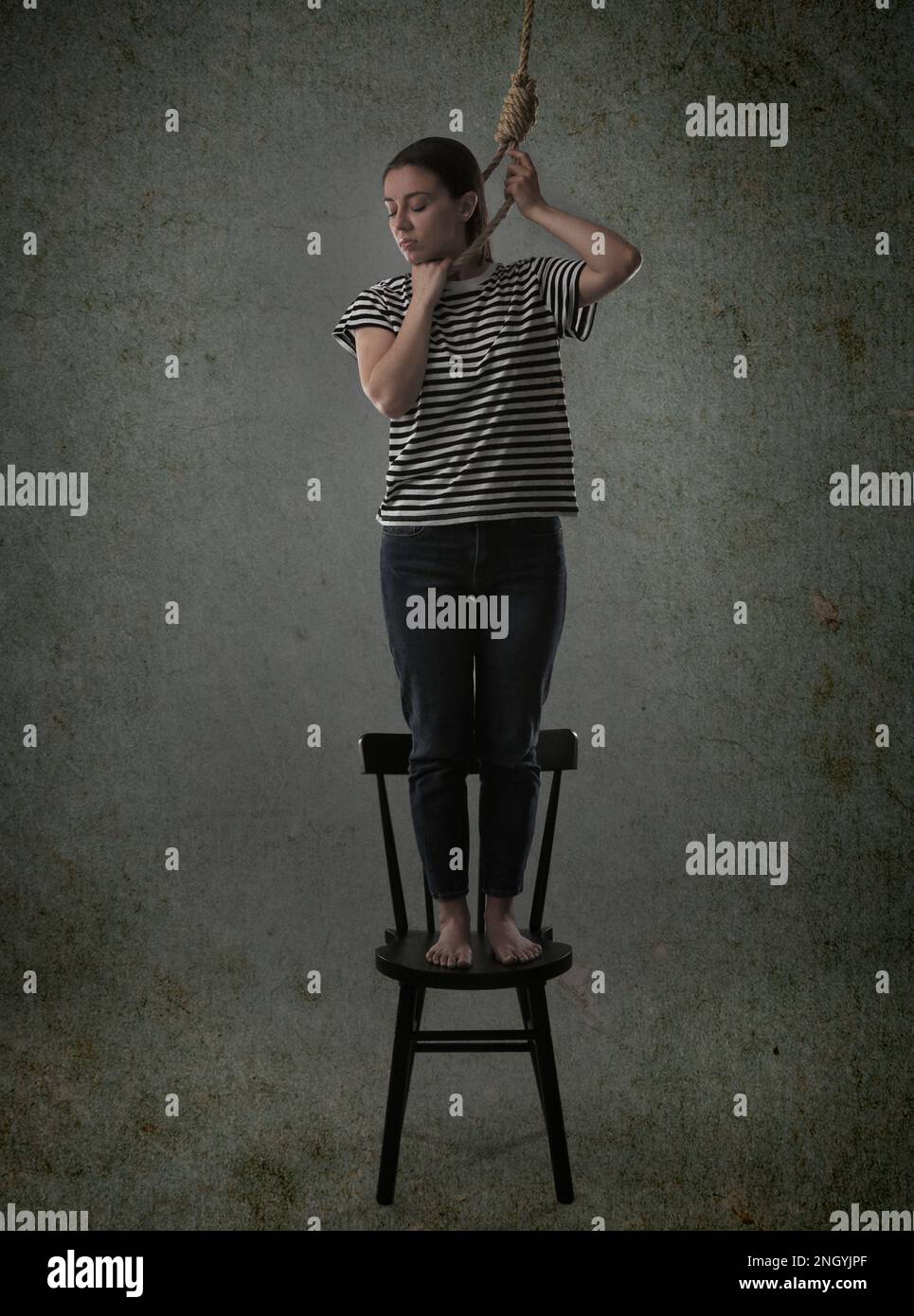 Depressed woman with rope noose standing on chair against grey ...