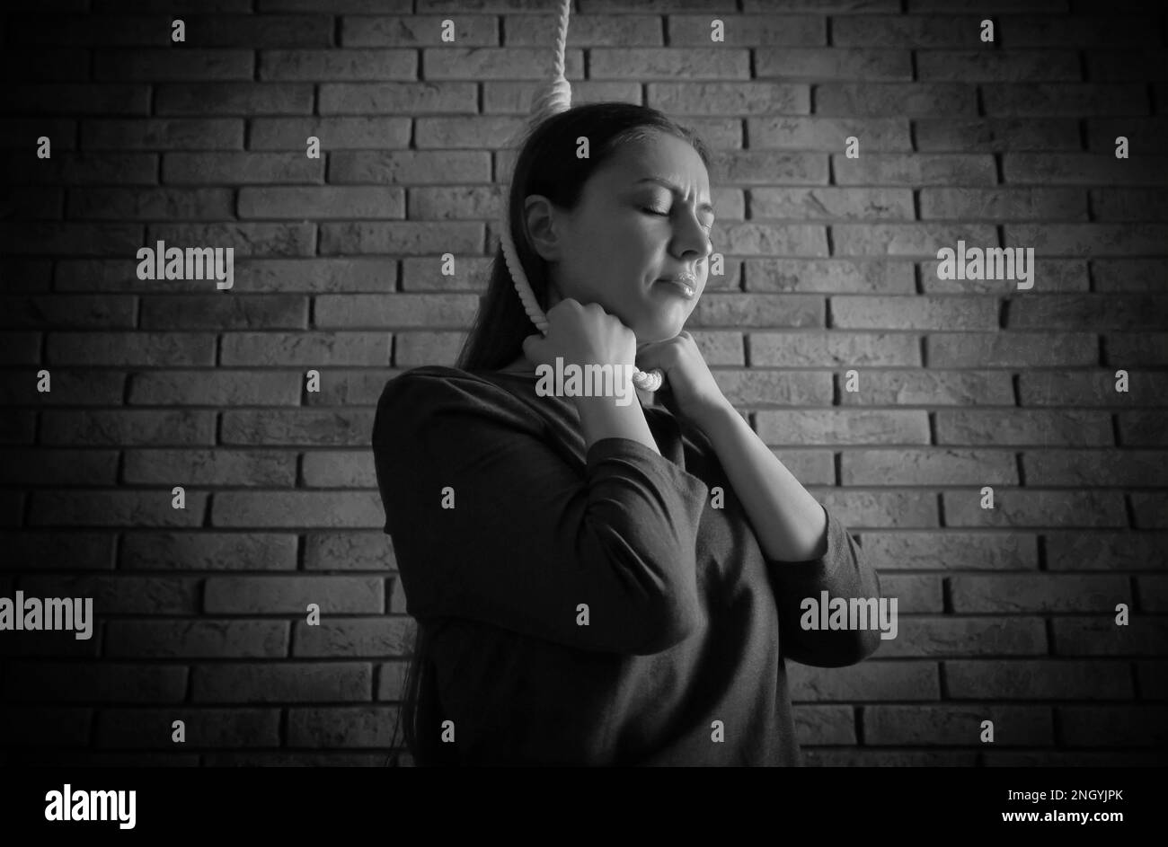Depressed woman with rope noose on neck near brick wall. Suicide ...