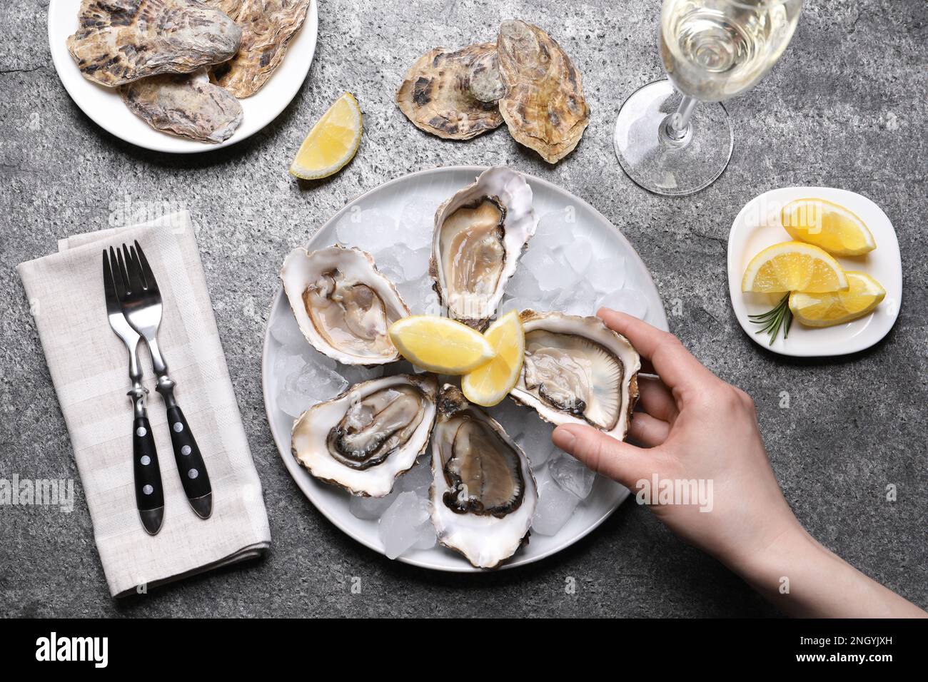 Woman eating tasty fresh oysters at grey table, top view Stock Photo ...