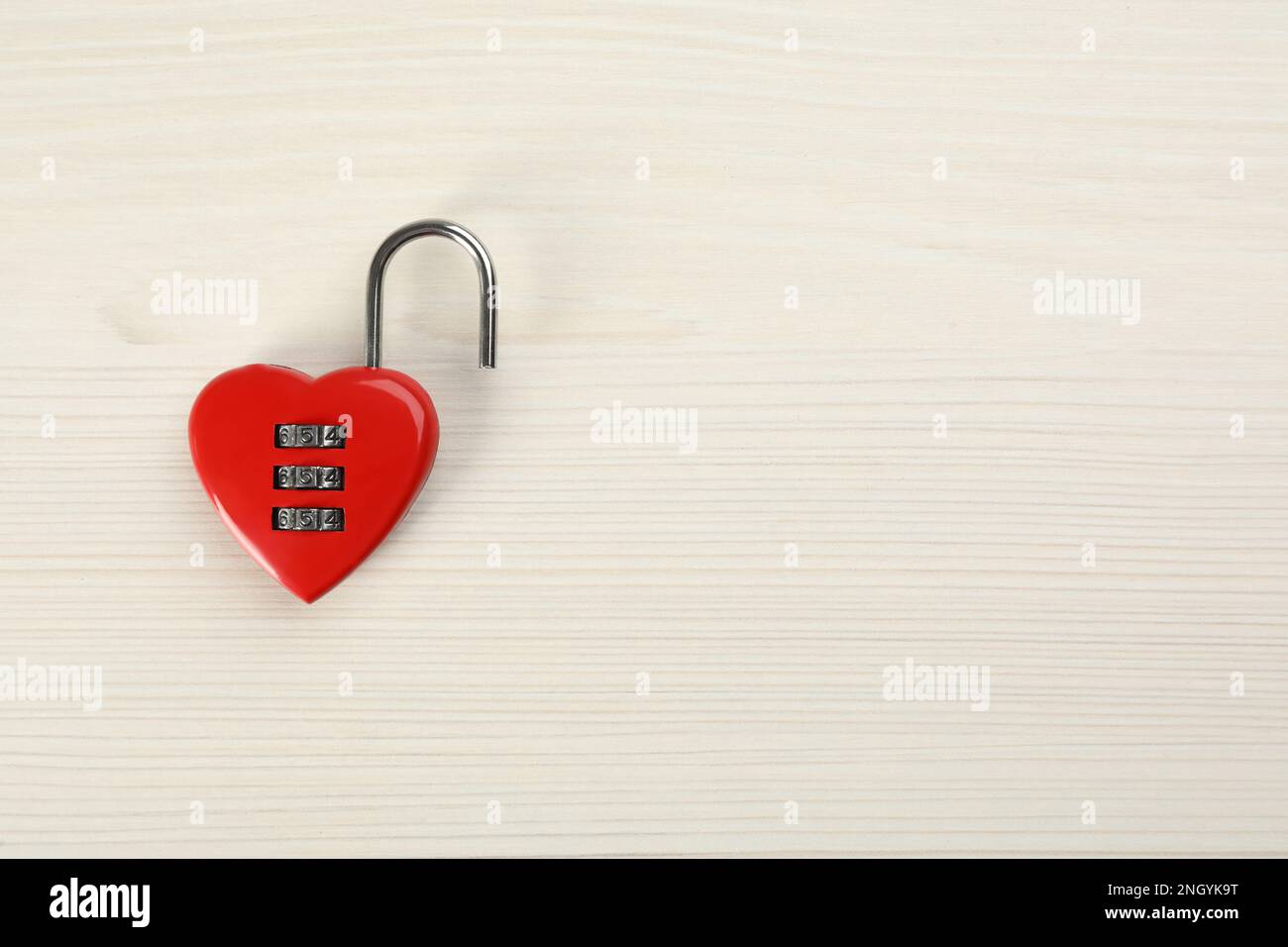 Red heart shaped combination lock on white wooden table, top view ...
