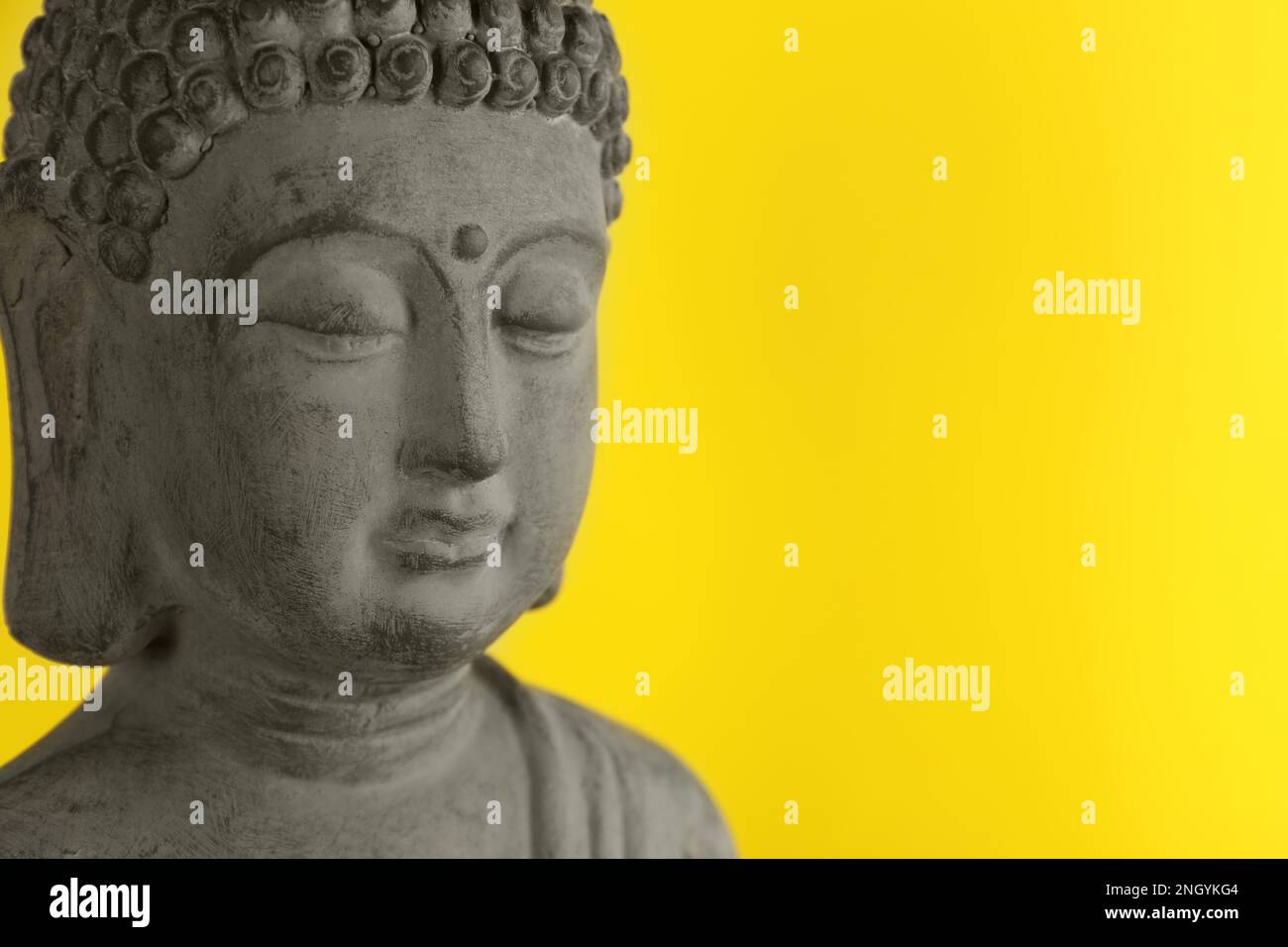 Beautiful stone Buddha sculpture on yellow background, closeup. Space ...