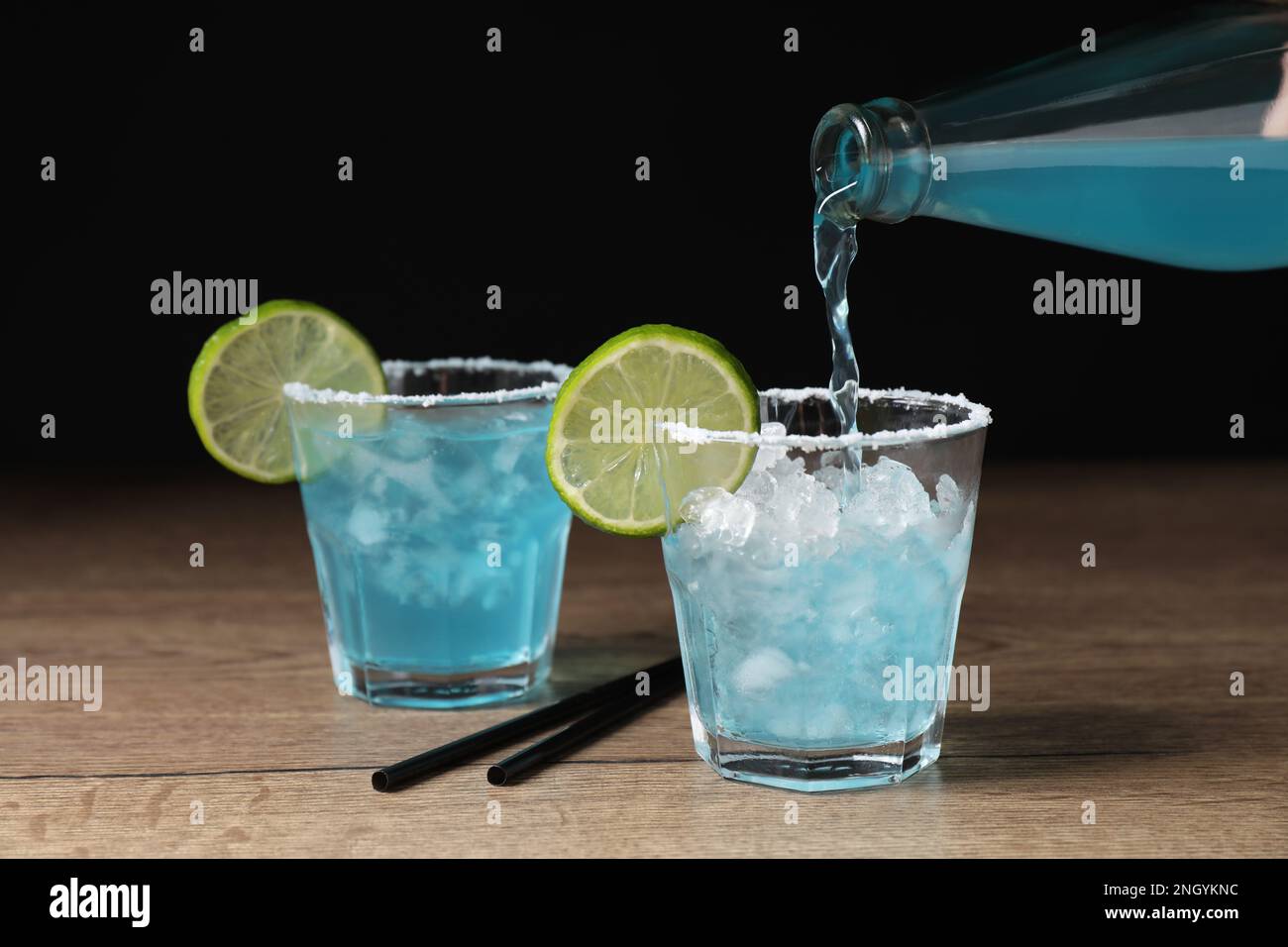 Pouring light blue drink into glass on wooden table Stock Photo - Alamy