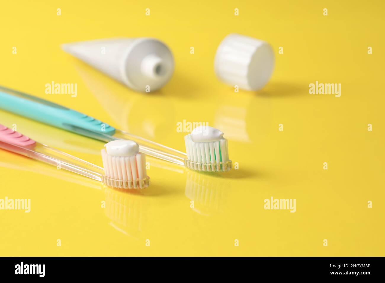 Brushes with toothpaste and tube on yellow background Stock Photo - Alamy