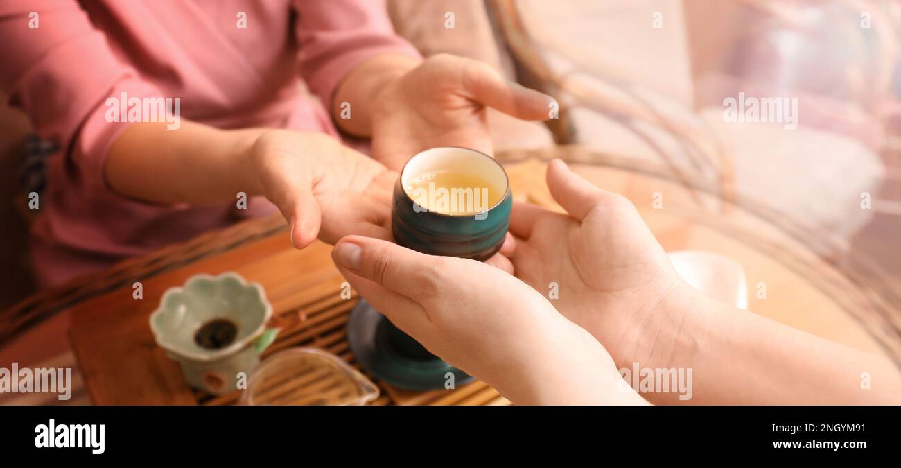 Woman giving cup with drink above table, closeup. Tea ceremony Stock ...
