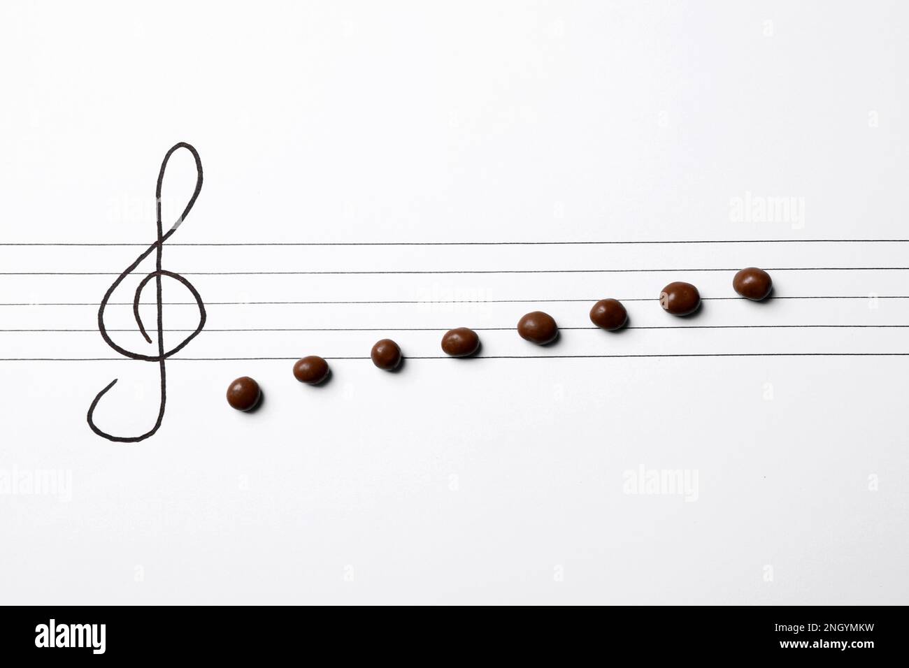 Music staff with treble clef and chocolate candies as notes on white ...