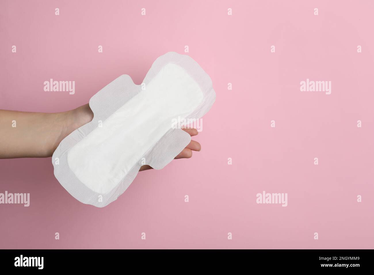 Woman holding sanitary napkin on pink background, closeup. Space for ...