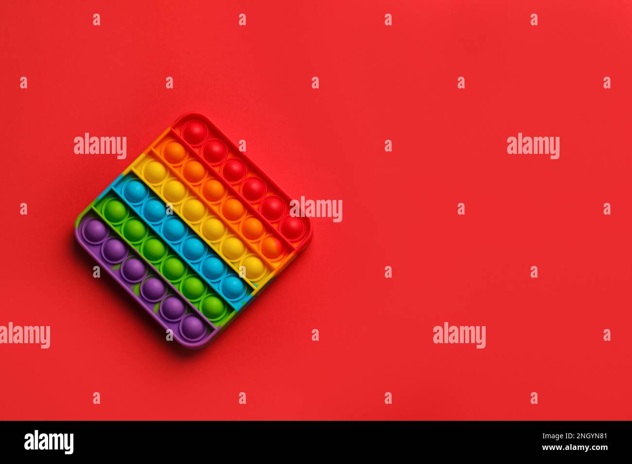 Rainbow pop it fidget toy on red background, top view. Space for text ...