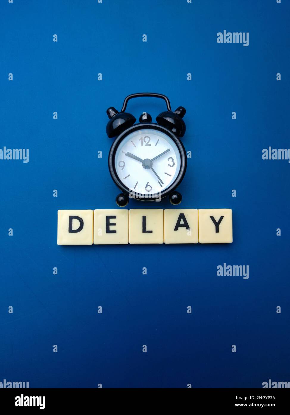 Black alarm clock with the word DELAY on blue background Stock Photo ...