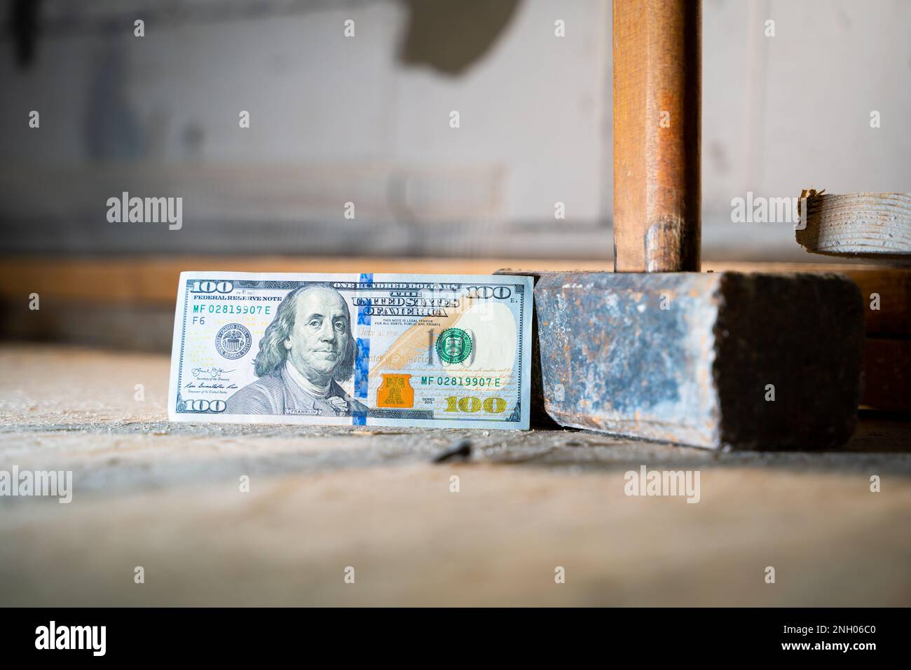 One hundred dollars and a large construction hammer close-up on a ...