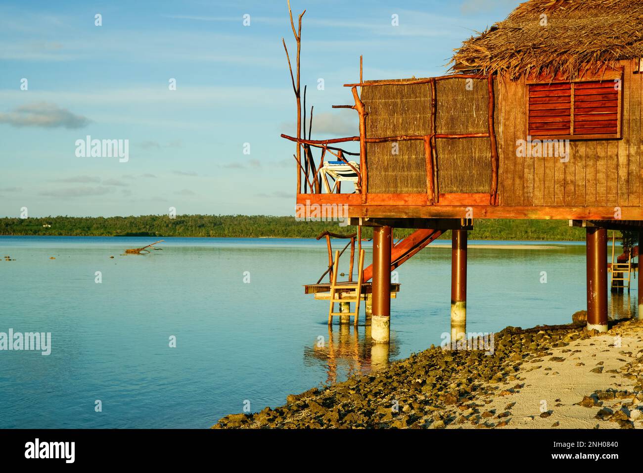 Idyllic tropical island scene of deck and chalet on poles at edge of ...