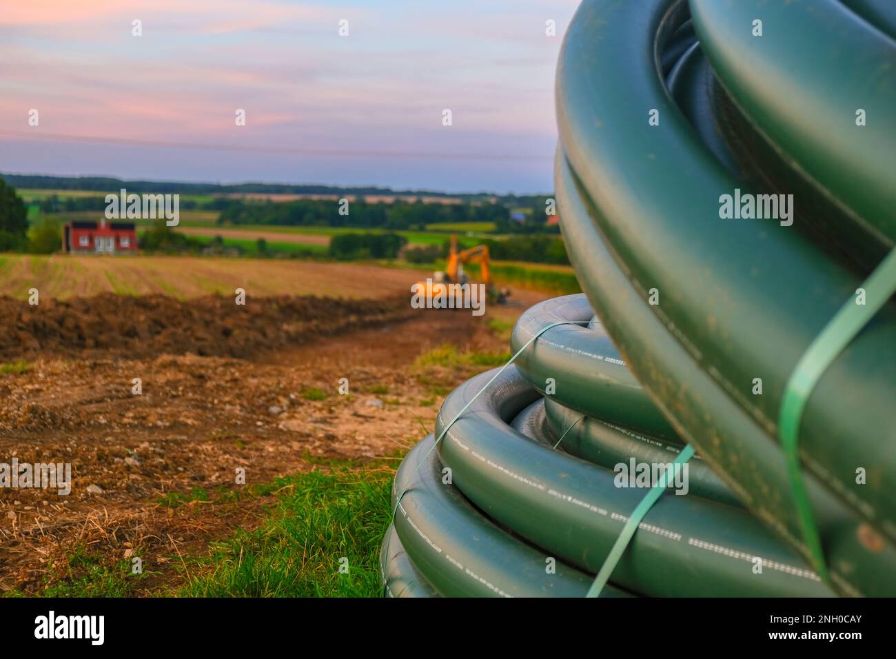 Water pipes and yellow excavator in the field. Carrying water ...