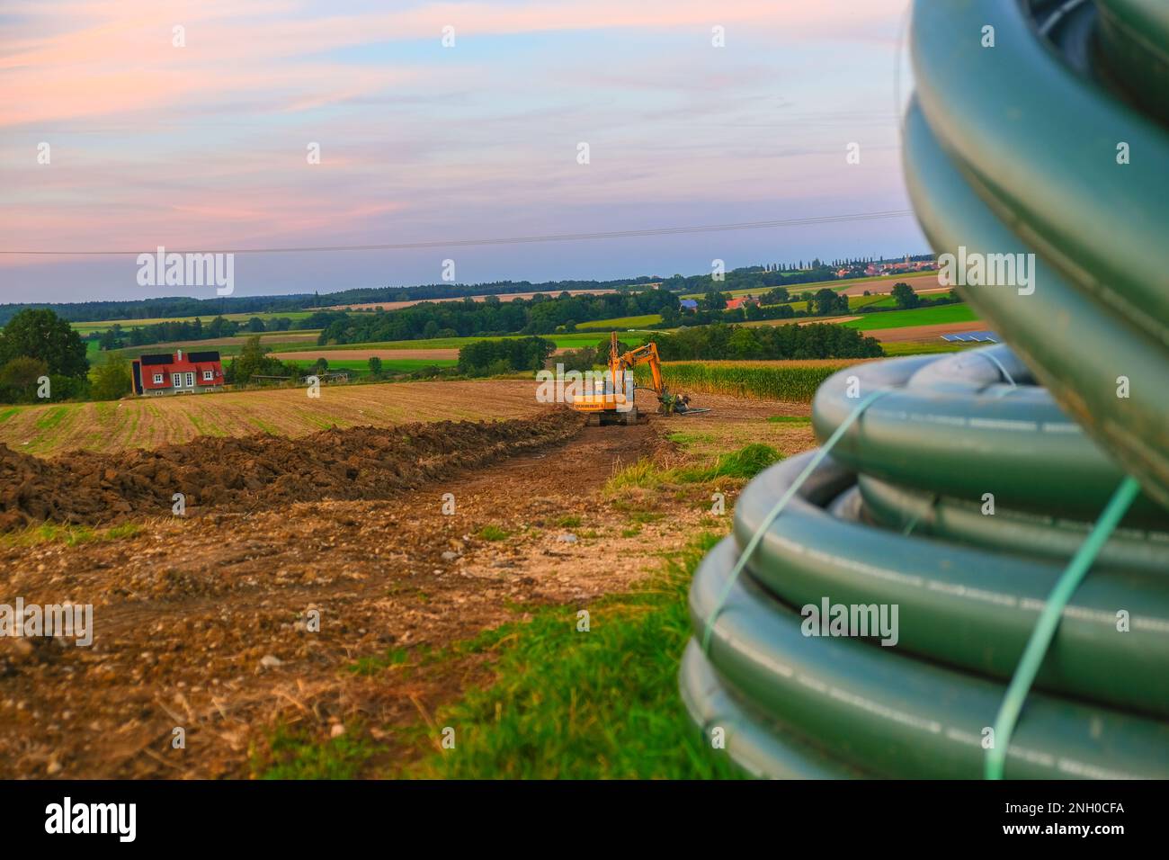 Pipe laying. Water pipes and yellow excavator in the field. Carrying ...