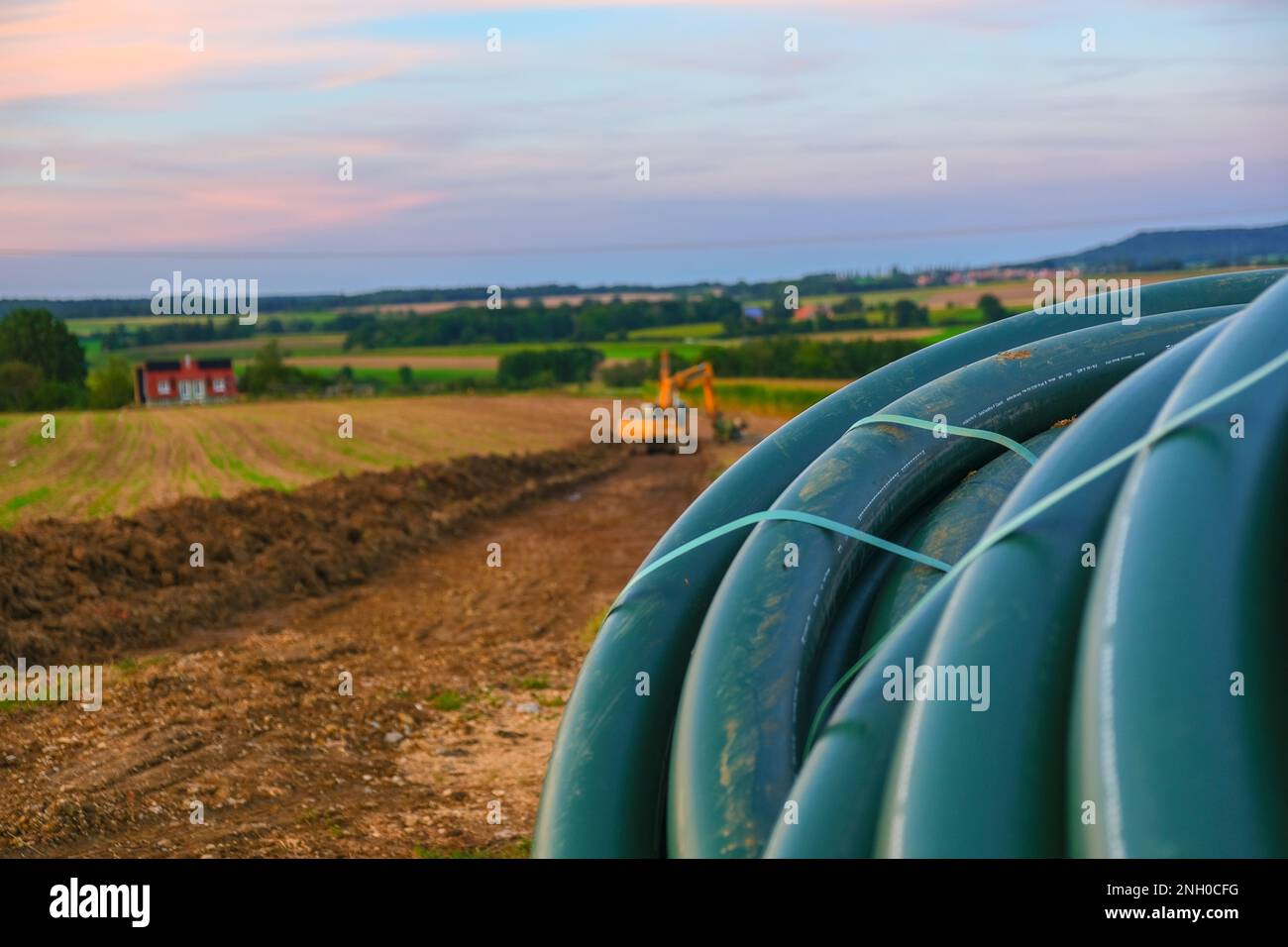 Plumbing installation. Pipe laying. Water pipes and yellow excavator in ...