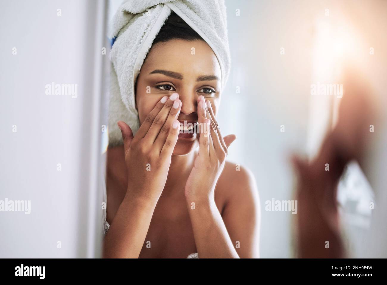 Giving her skin a good pamper. an attractive young woman applying ...