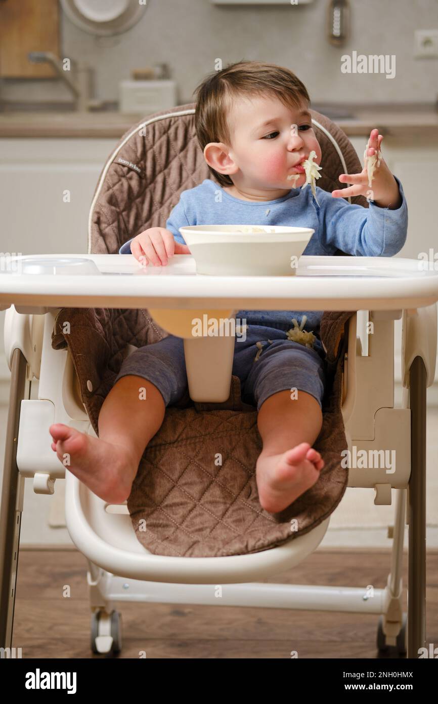 A funny child is eating a grated apple with his mouth full while ...