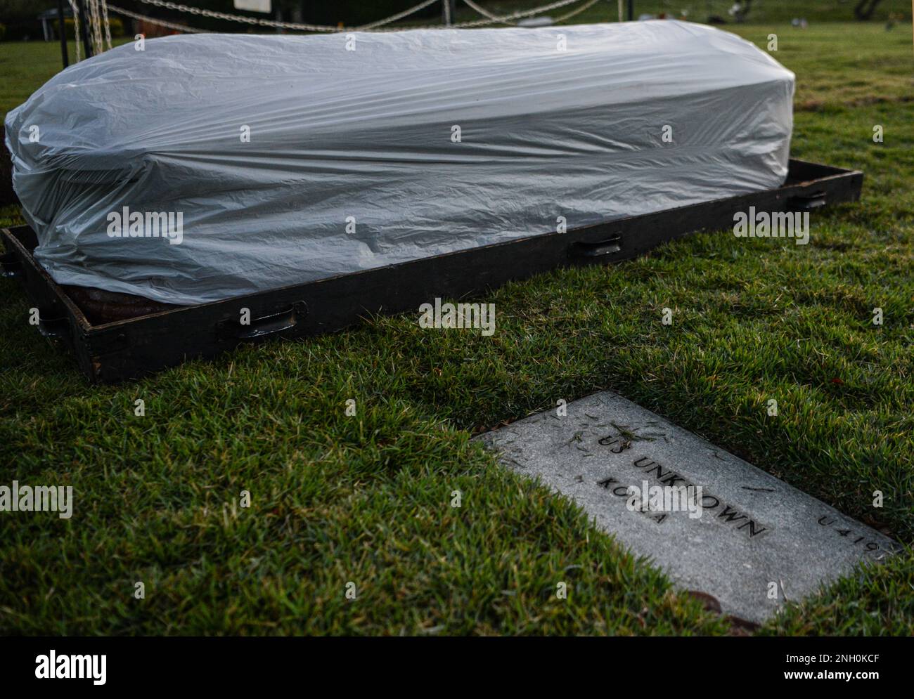 A Korean War coffin lies next to a headstone of an unknown during a ...