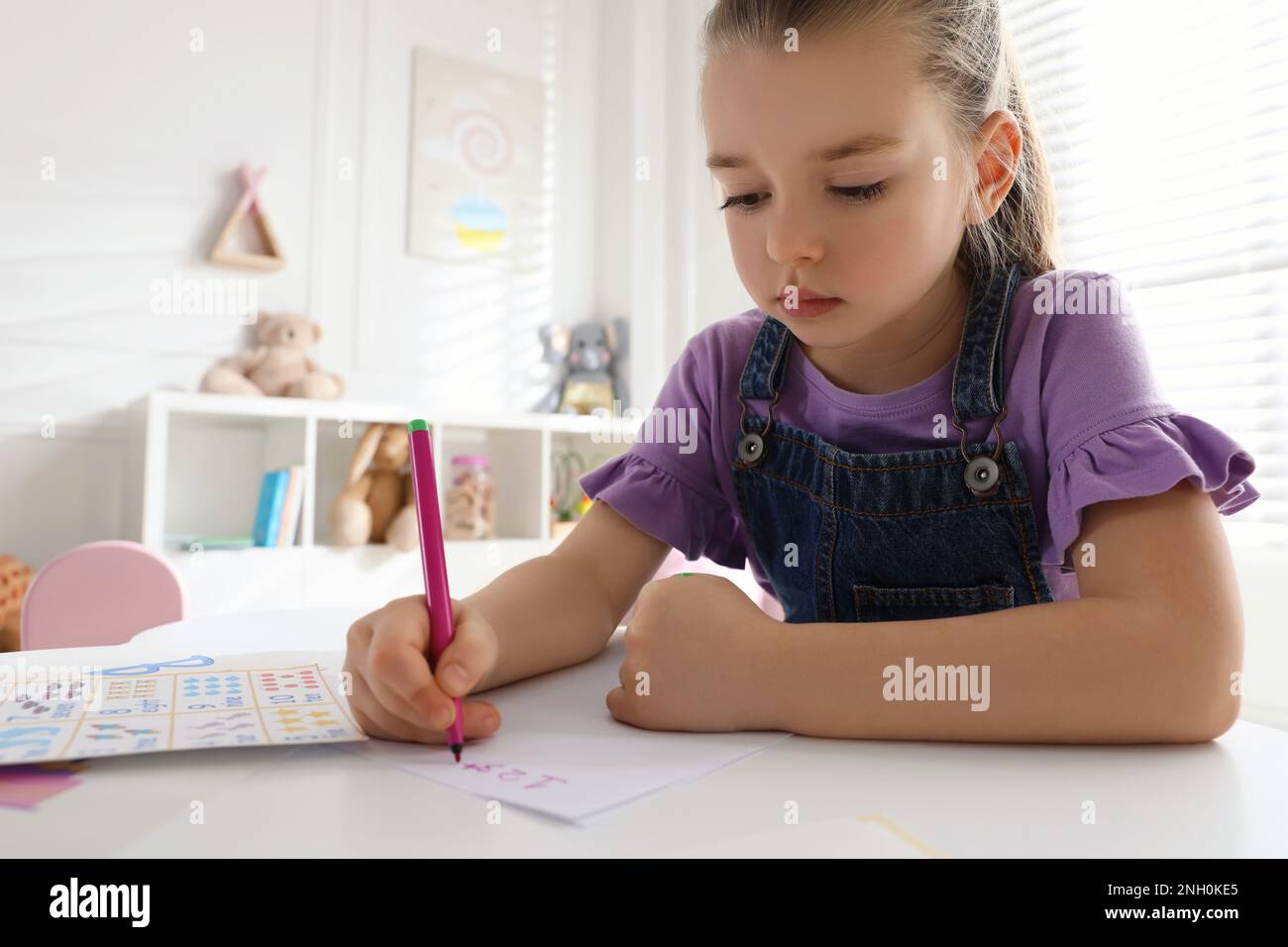 Little girl writing numbers in classroom at English lesson Stock Photo ...