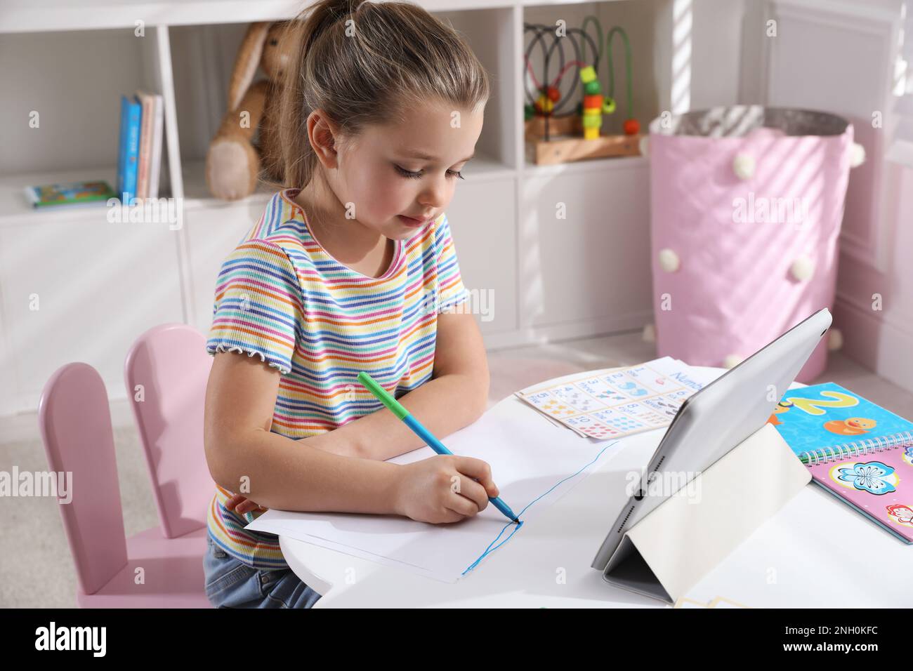 Little girl learning English with tablet indoors at online lesson Stock ...