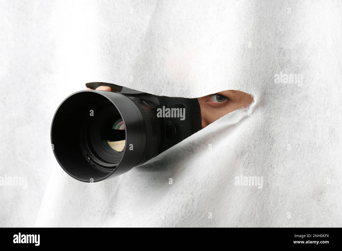 Hidden woman with camera spying through hole in white fabric Stock ...