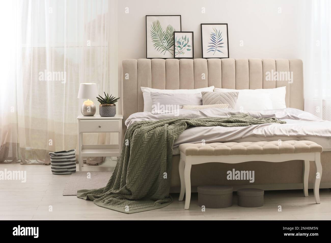 Bed with stylish grey linens near white wall in room Stock Photo - Alamy