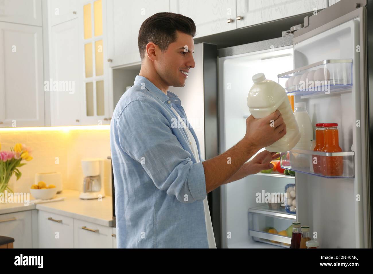 Man putting gallon of milk into refrigerator in kitchen Stock Photo - Alamy