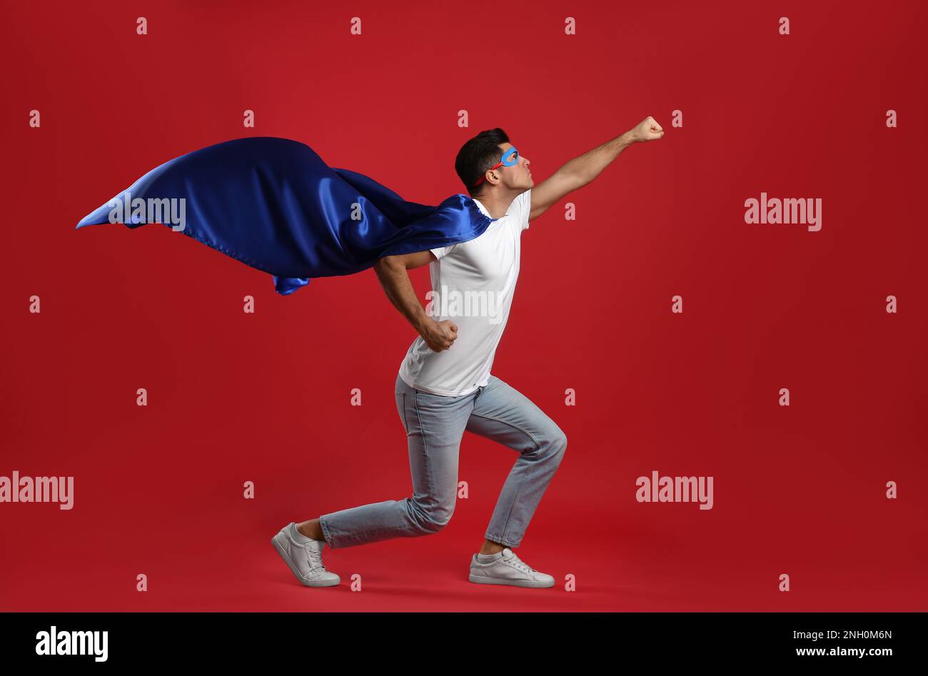 Man wearing superhero cape and mask on red background Stock Photo - Alamy