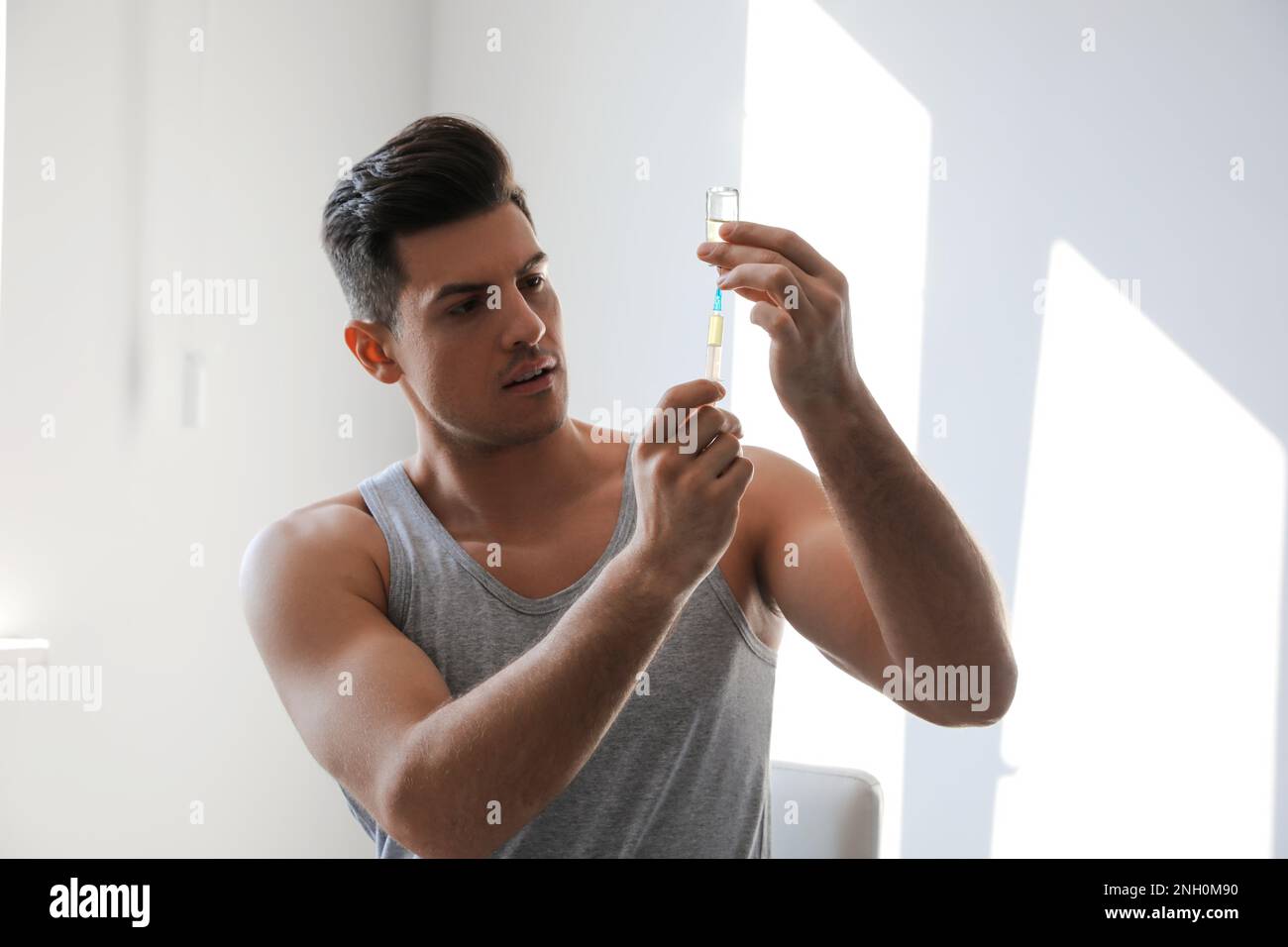 Athletic man filling syringe indoors. Doping concept Stock Photo - Alamy