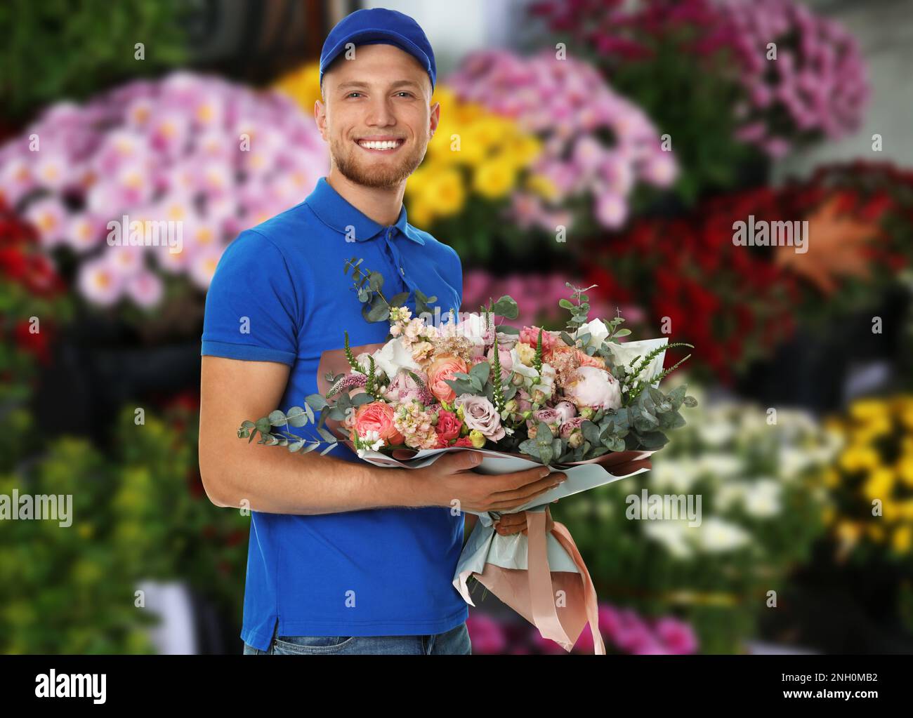 Delivery man with beautiful bouquet in flower shop Stock Photo - Alamy
