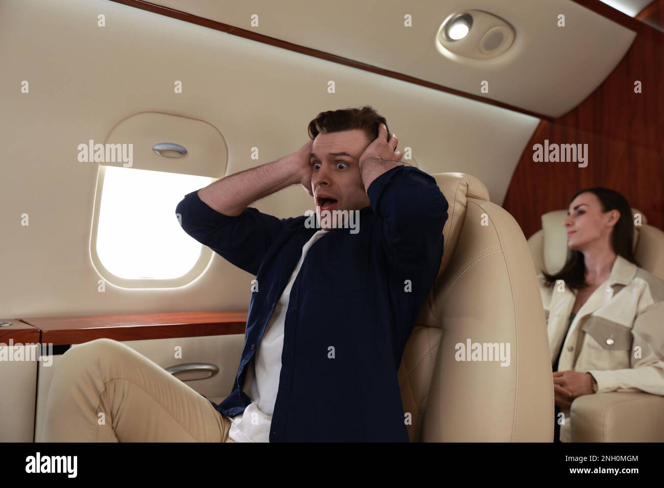 Scared young man suffering from aviophobia in airplane Stock Photo - Alamy