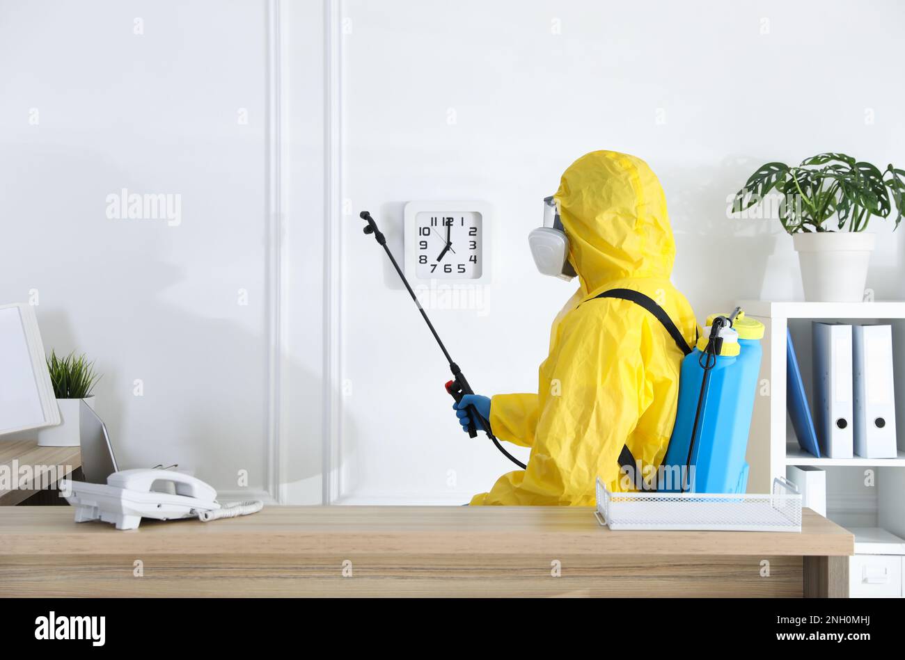 Employee in protective suit sanitizing office. Medical disinfection ...