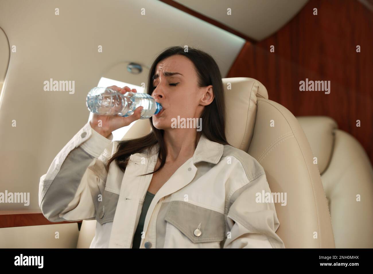 Nervous young woman with aviophobia drinking water in airplane Stock ...