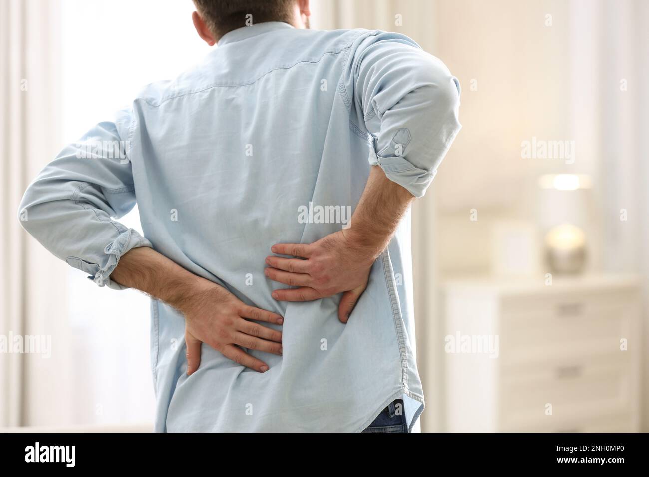Man suffering from back pain at home, closeup. Bad posture problem ...
