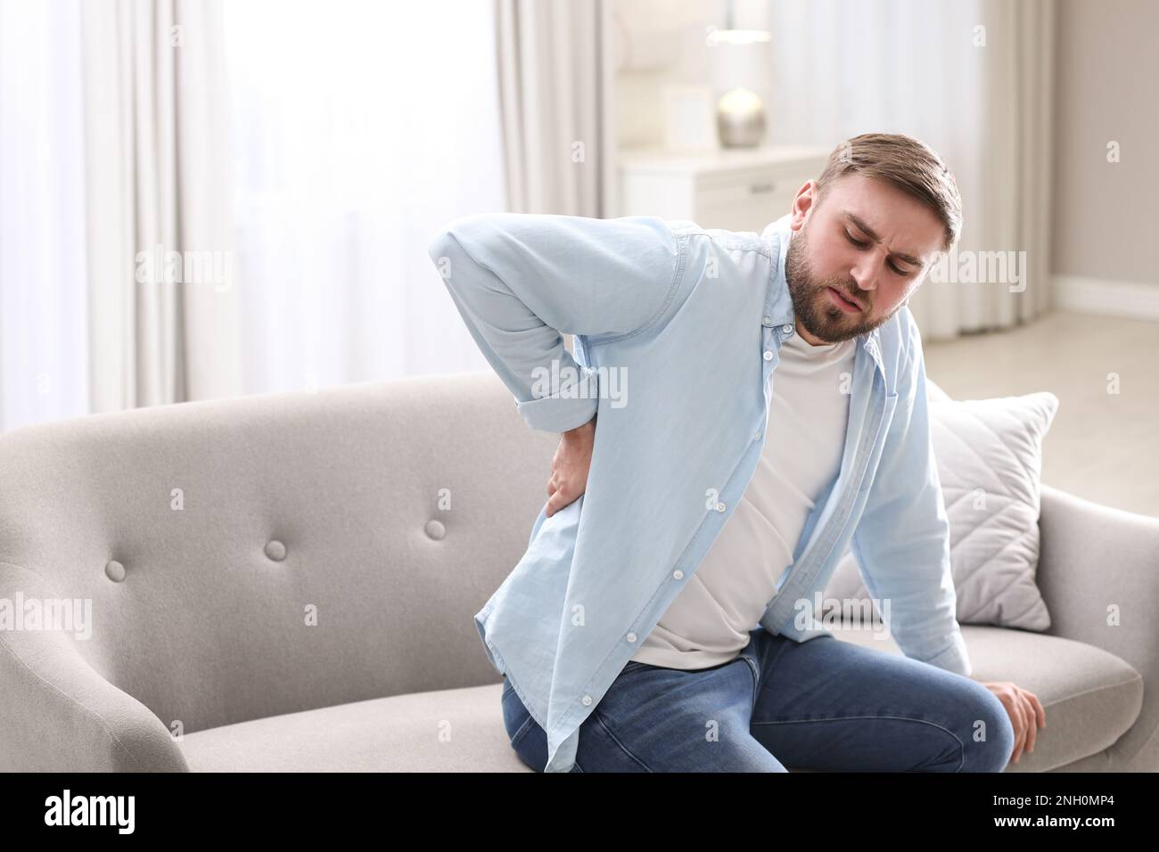 Man suffering from back pain at home. Bad posture problem Stock Photo ...