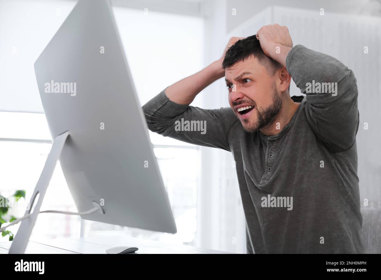 Emotional man in front of computer at workplace. Online hate concept ...