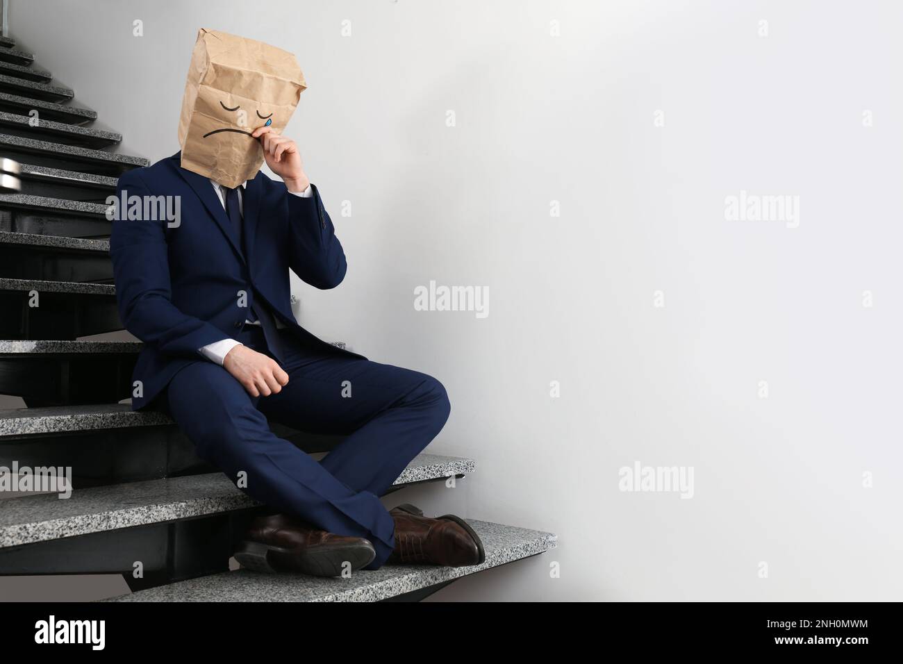 Man wearing paper bag with drawn sad face indoors. Space for text Stock ...