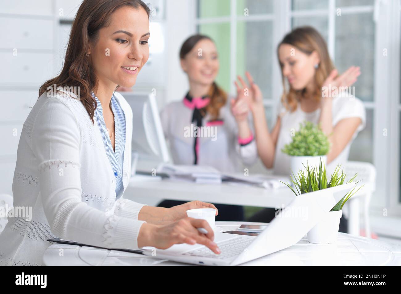 young women sit at the table and work in a modern office Stock Photo ...