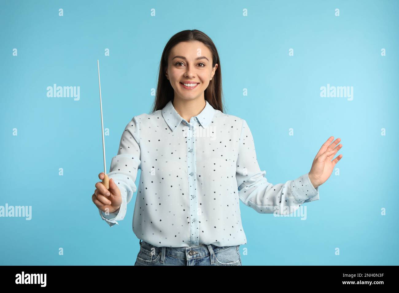 Music teacher with baton on turquoise background Stock Photo - Alamy