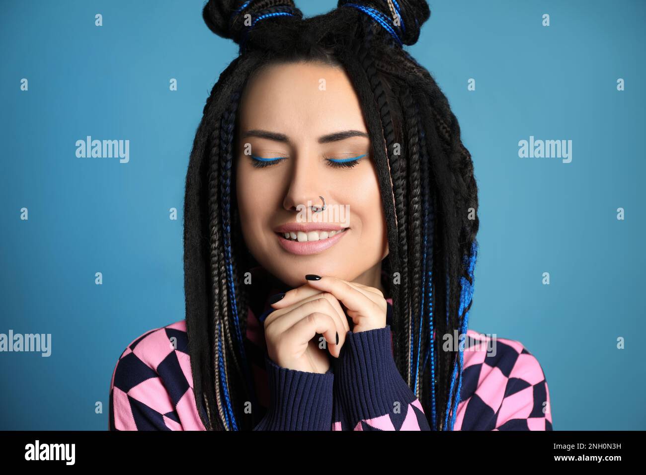 Beautiful young woman with nose piercing and dreadlocks on light blue ...