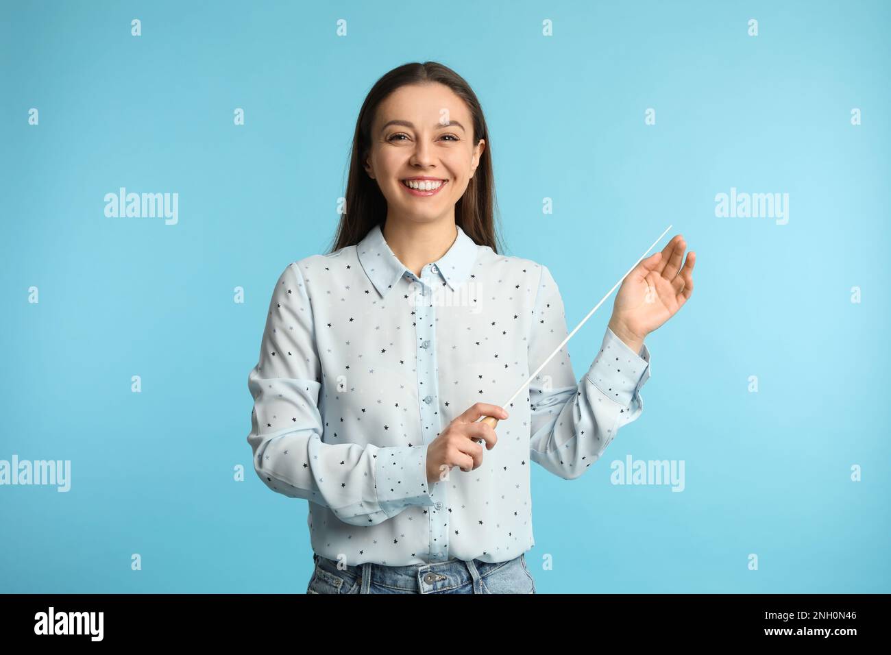 Music teacher with baton on turquoise background Stock Photo - Alamy
