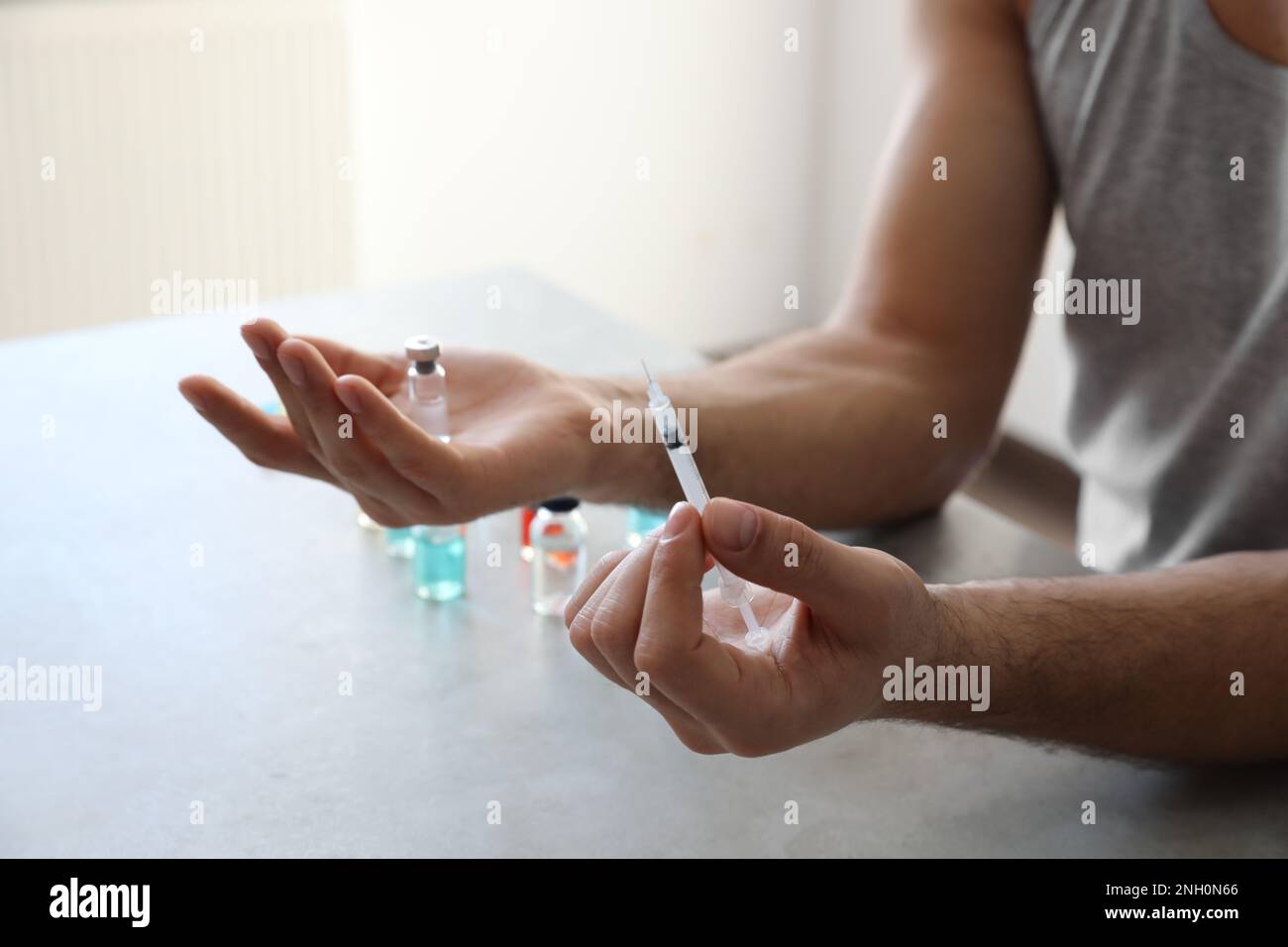 Man with syringe and vial at grey table, closeup. Doping concept Stock ...