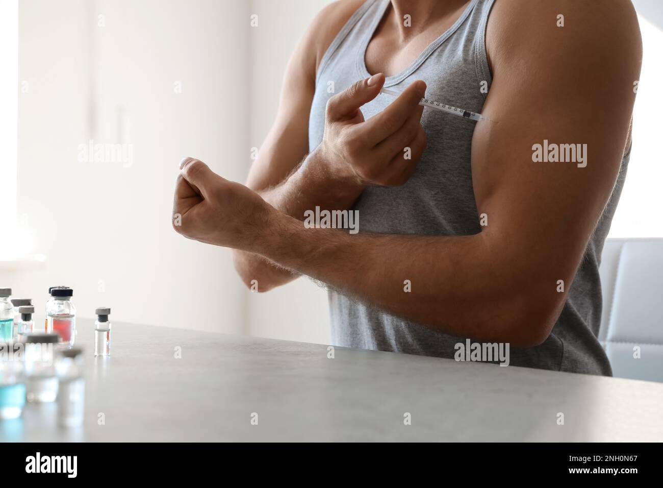 Athletic man injecting himself at table indoors, closeup. Doping ...