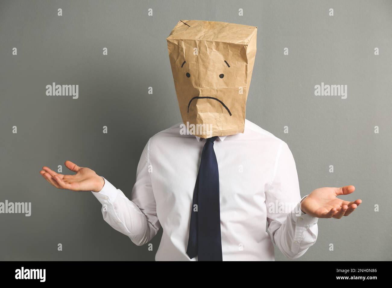 Man wearing paper bag with drawn sad face on grey background Stock ...