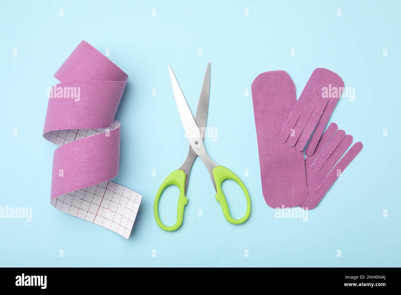 Bright kinesio tape pieces and scissors on light blue background, flat ...