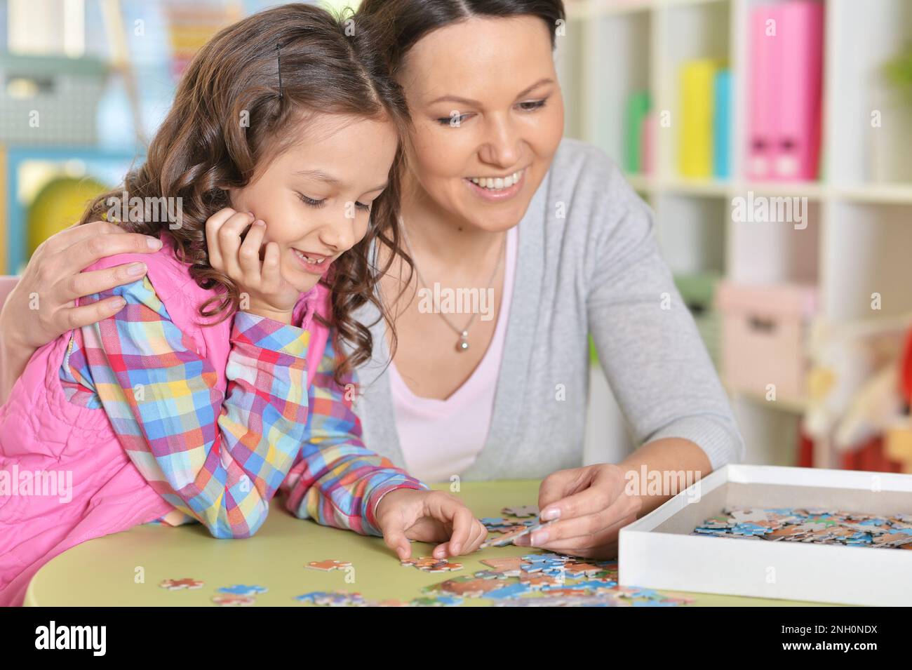 Mother with little daughter collecting puzzle Stock Photo - Alamy