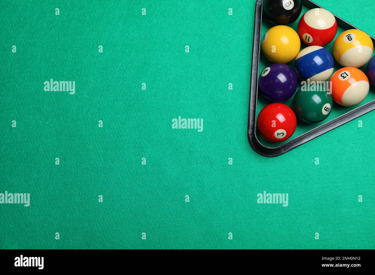 Plastic rack with billiard balls on green table, top view. Space for ...