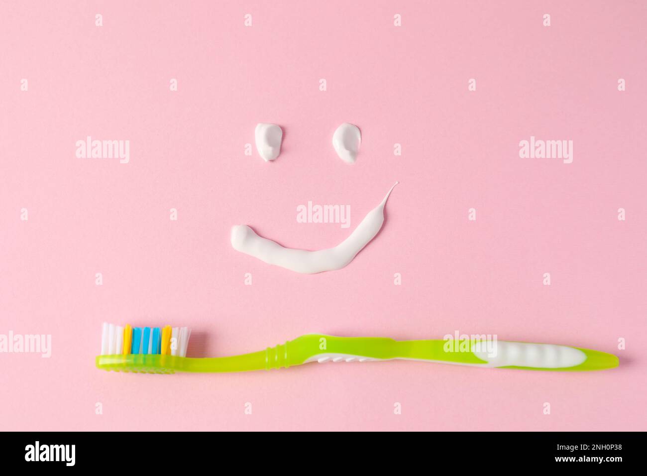 Funny face made with toothpaste and brush on pink background, flat lay ...